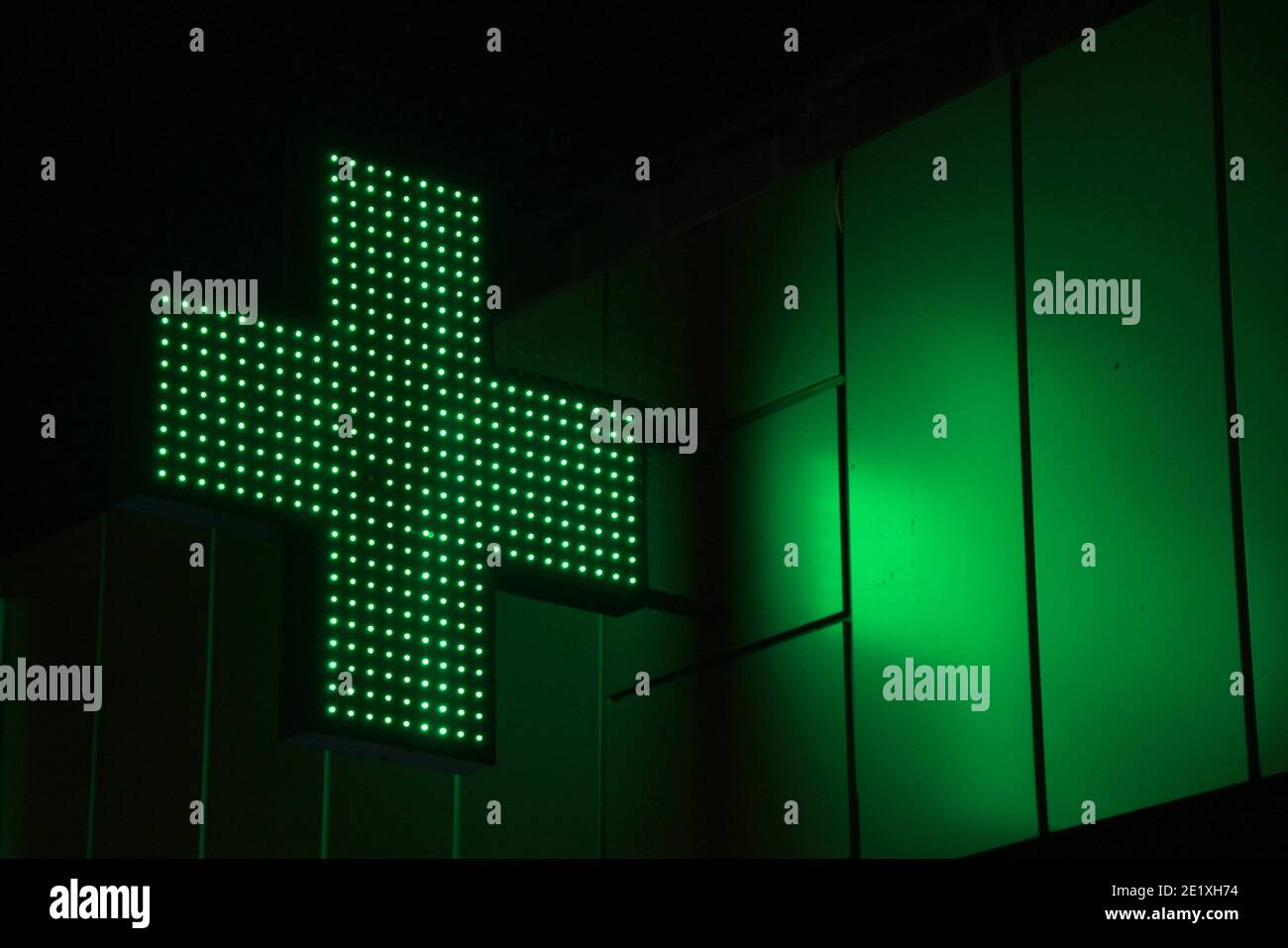 Glowing pixel cross of LED lamps on black background. Green cross ...