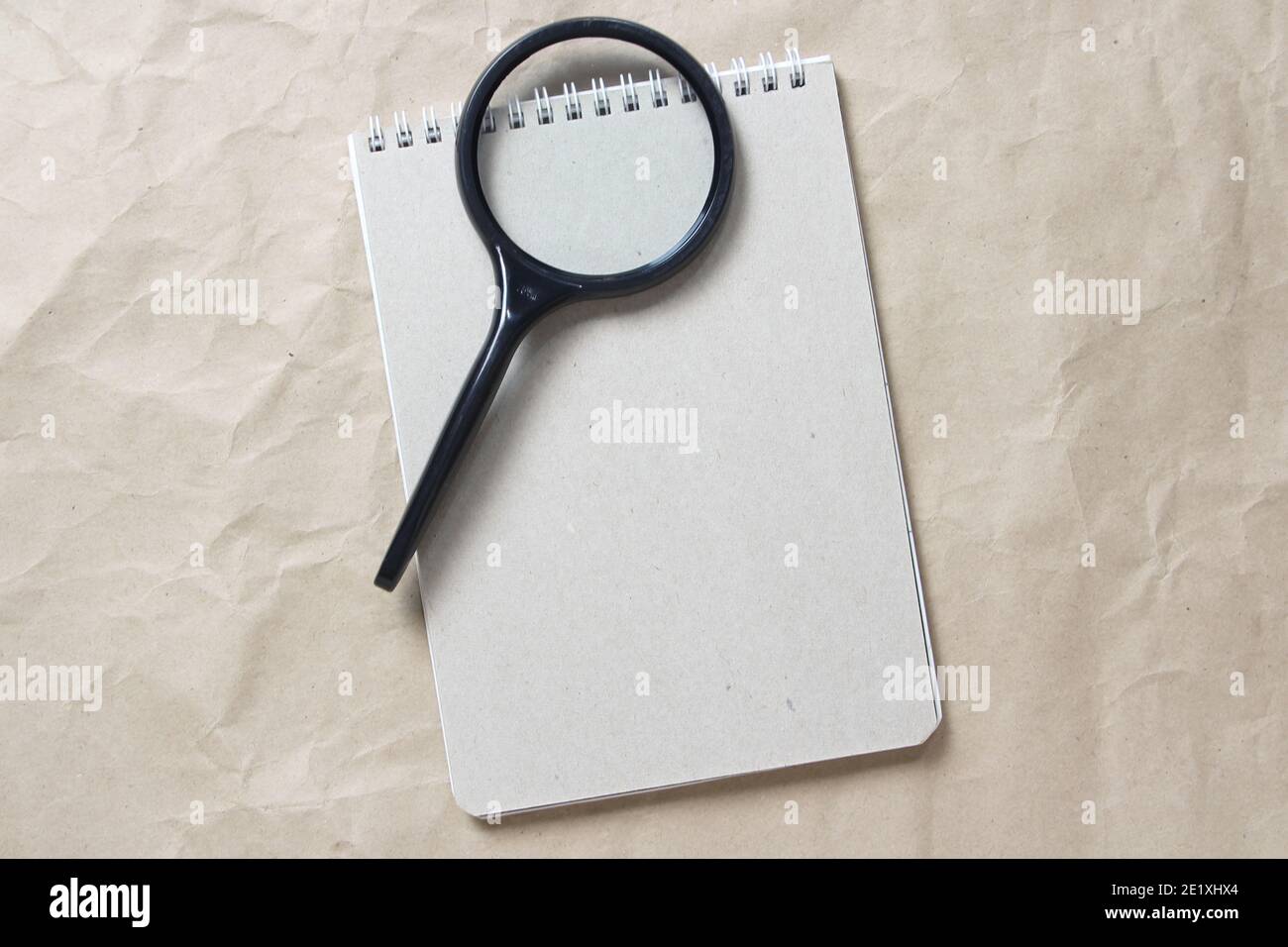 Gray notepad with white coiled spring and magnifier on a background of ...