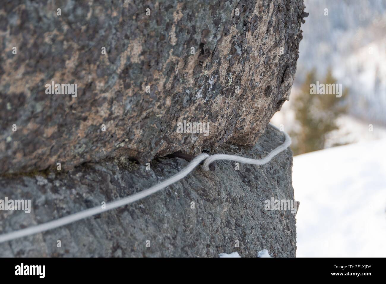 Rope is attached to boulder. Safety rope for rock climbers along rocky ...