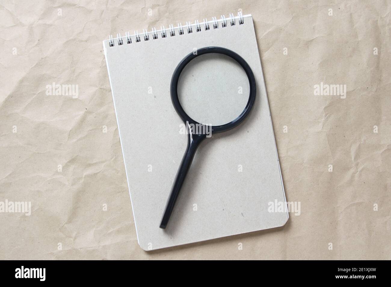 Gray notepad with white coiled spring and magnifier on a background of ...