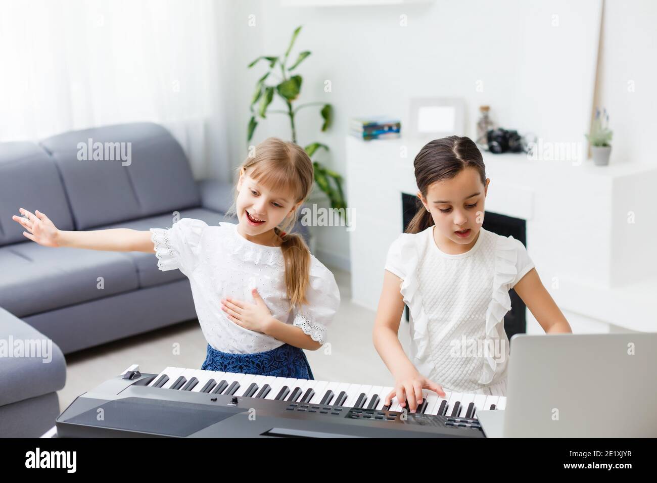 Home piano lesson. two girls practice sheet music on one musical ...