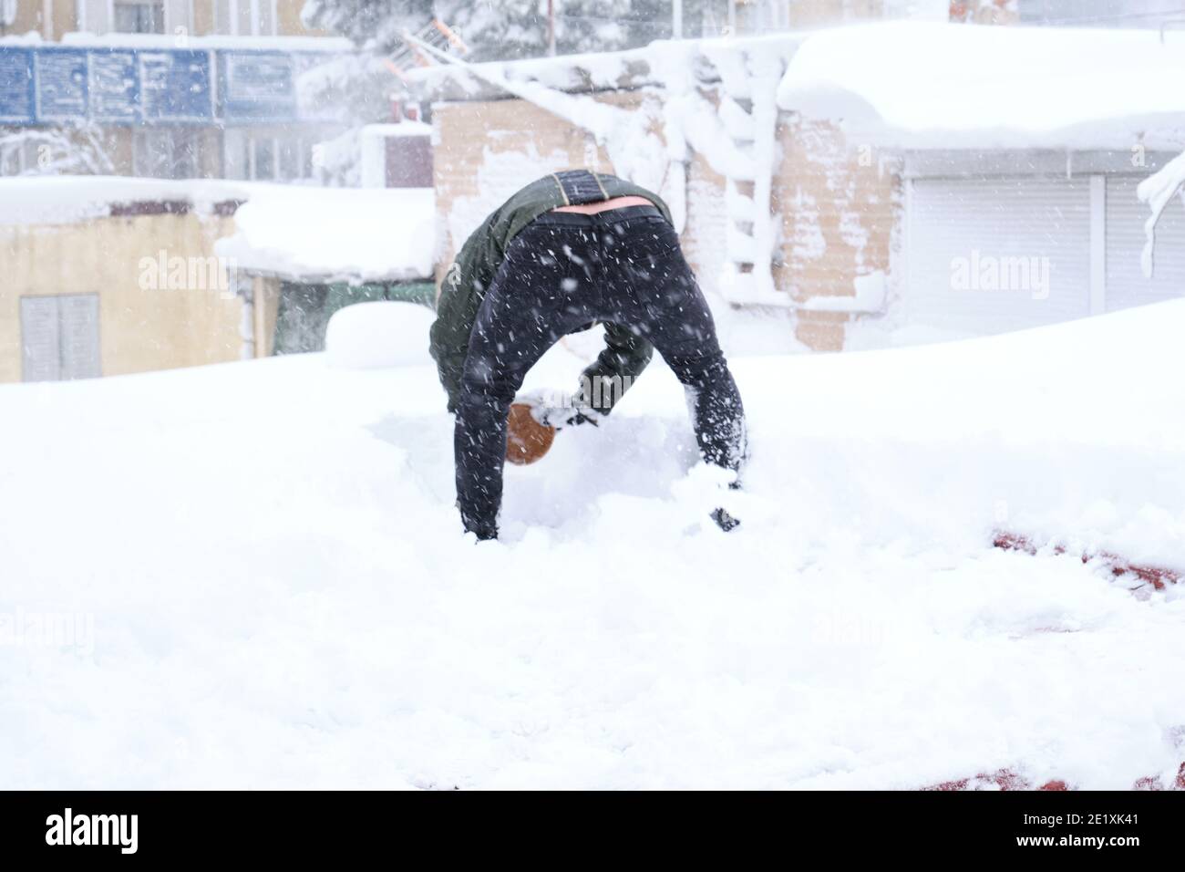 Man removing snow from the roof of his house. Snowstorm, blizzard in ...