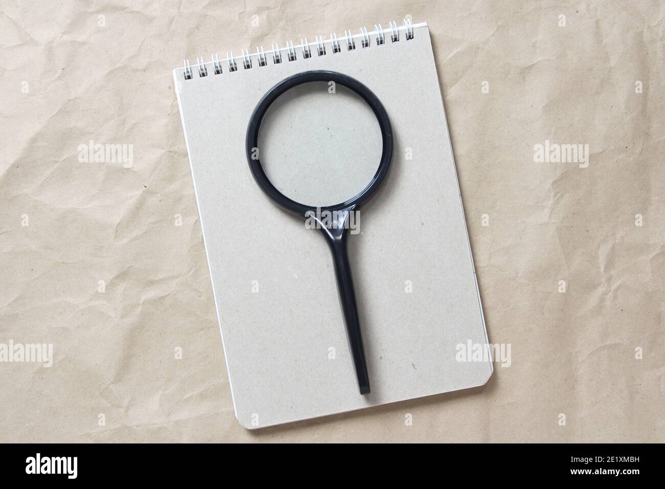 Gray notepad with white coiled spring and magnifier on a background of ...