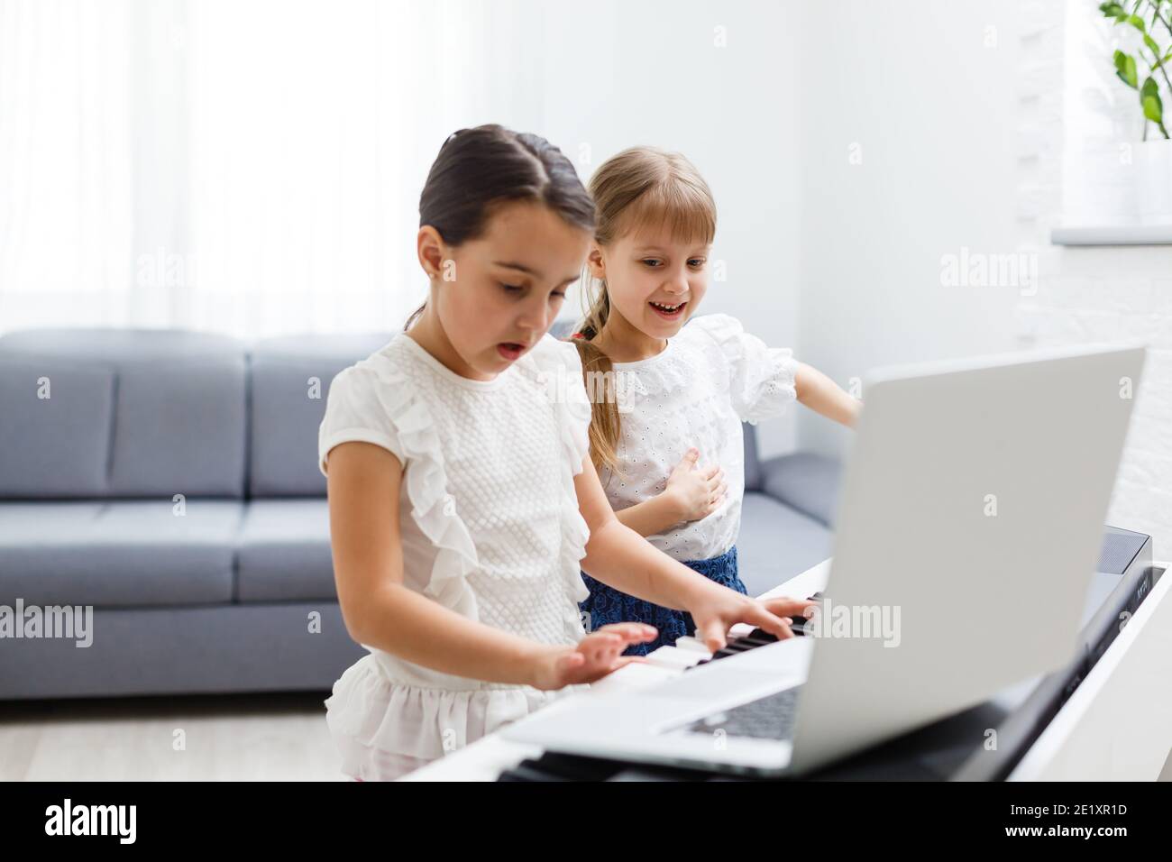 Home piano lesson. two girls practice sheet music on one musical ...