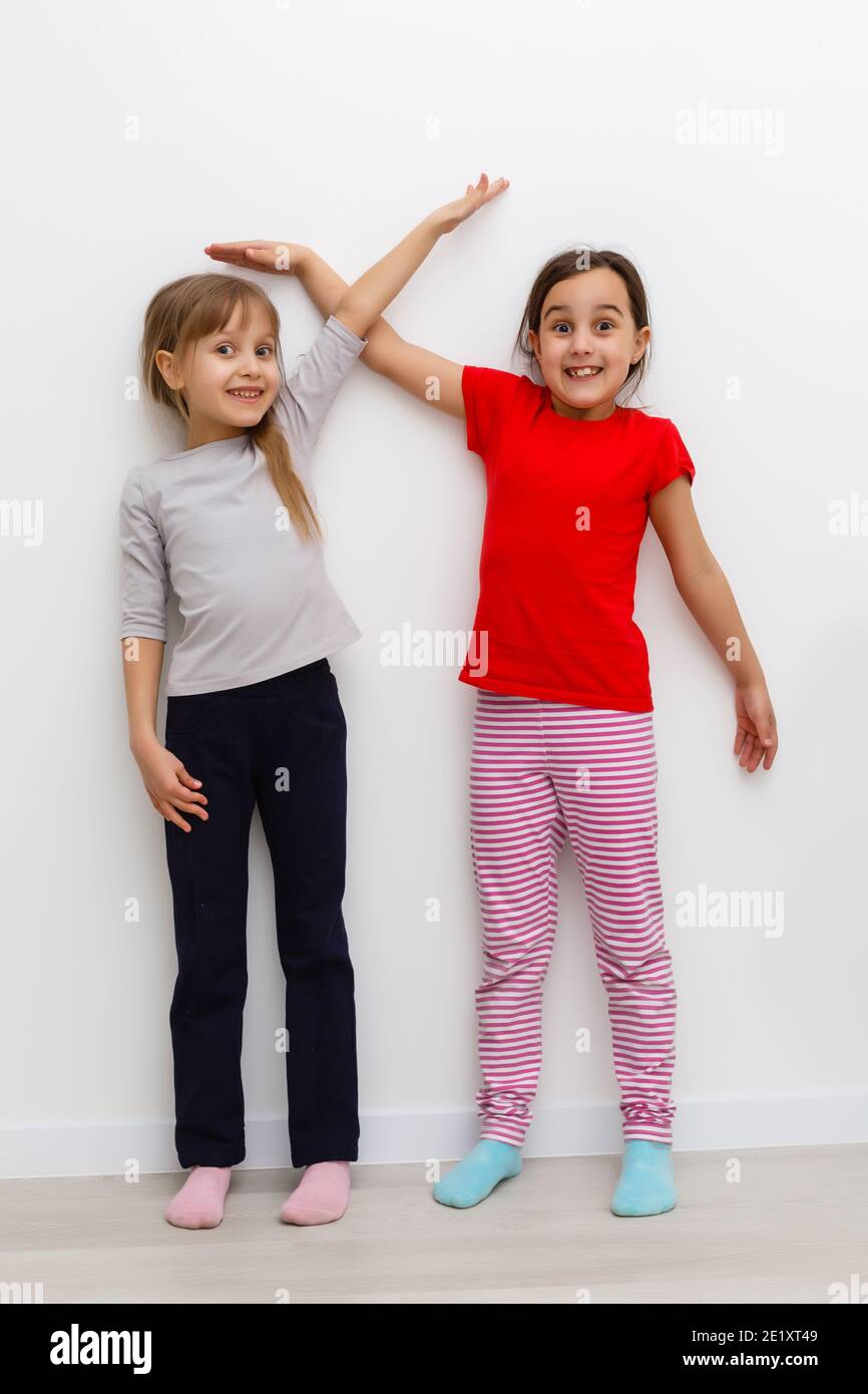 Two girls stretch up with hand on scale Stock Photo - Alamy