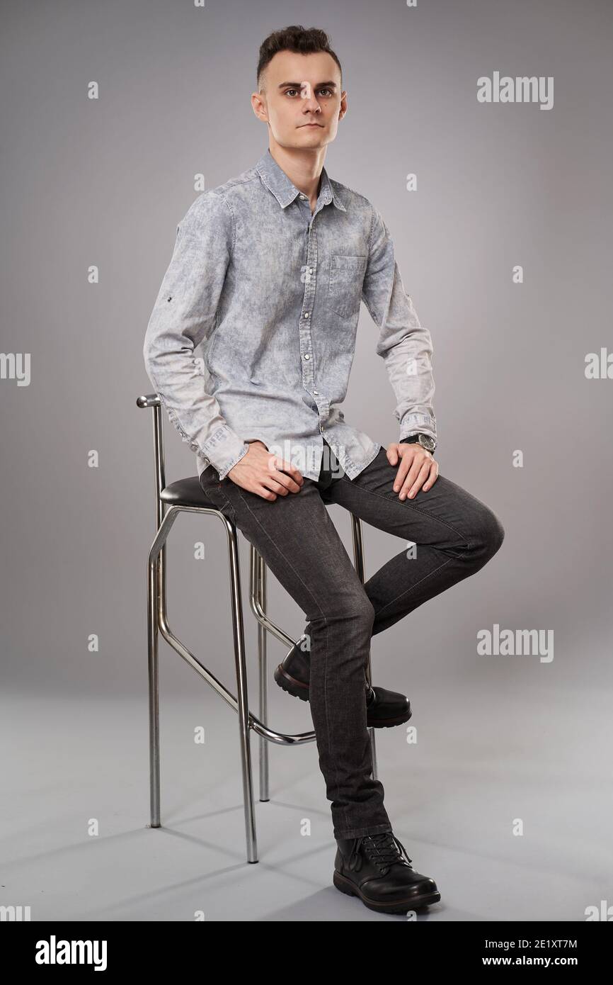 Full body shot of a young businessman sitting on a high chair Stock ...