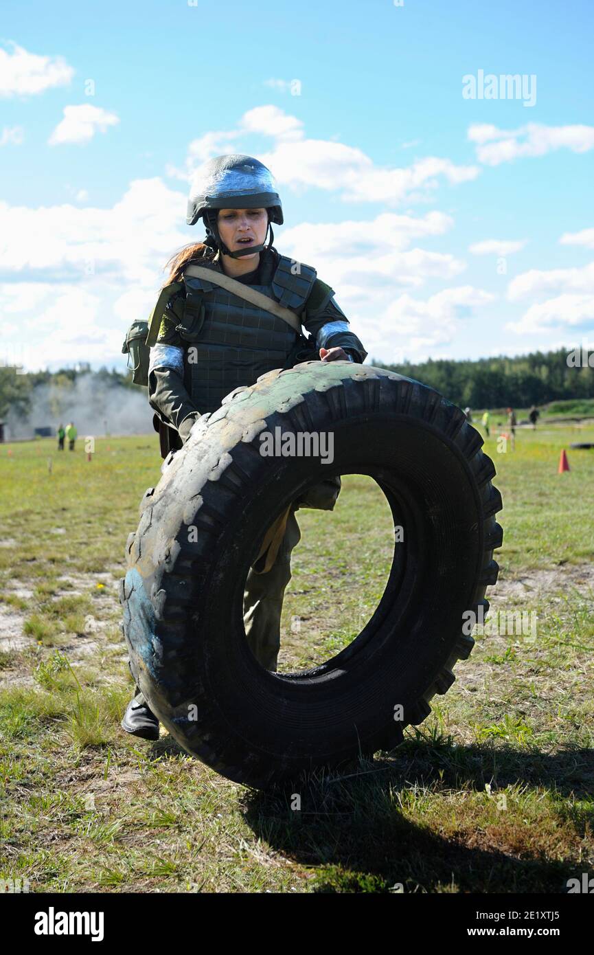 Fully equipped female soldier pushing large tire overcoming obstacle ...