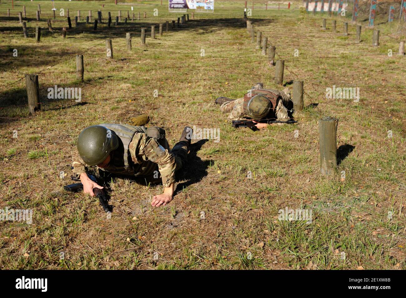 Overcoming obstacle course: fully equipped soldiers crawling under ...