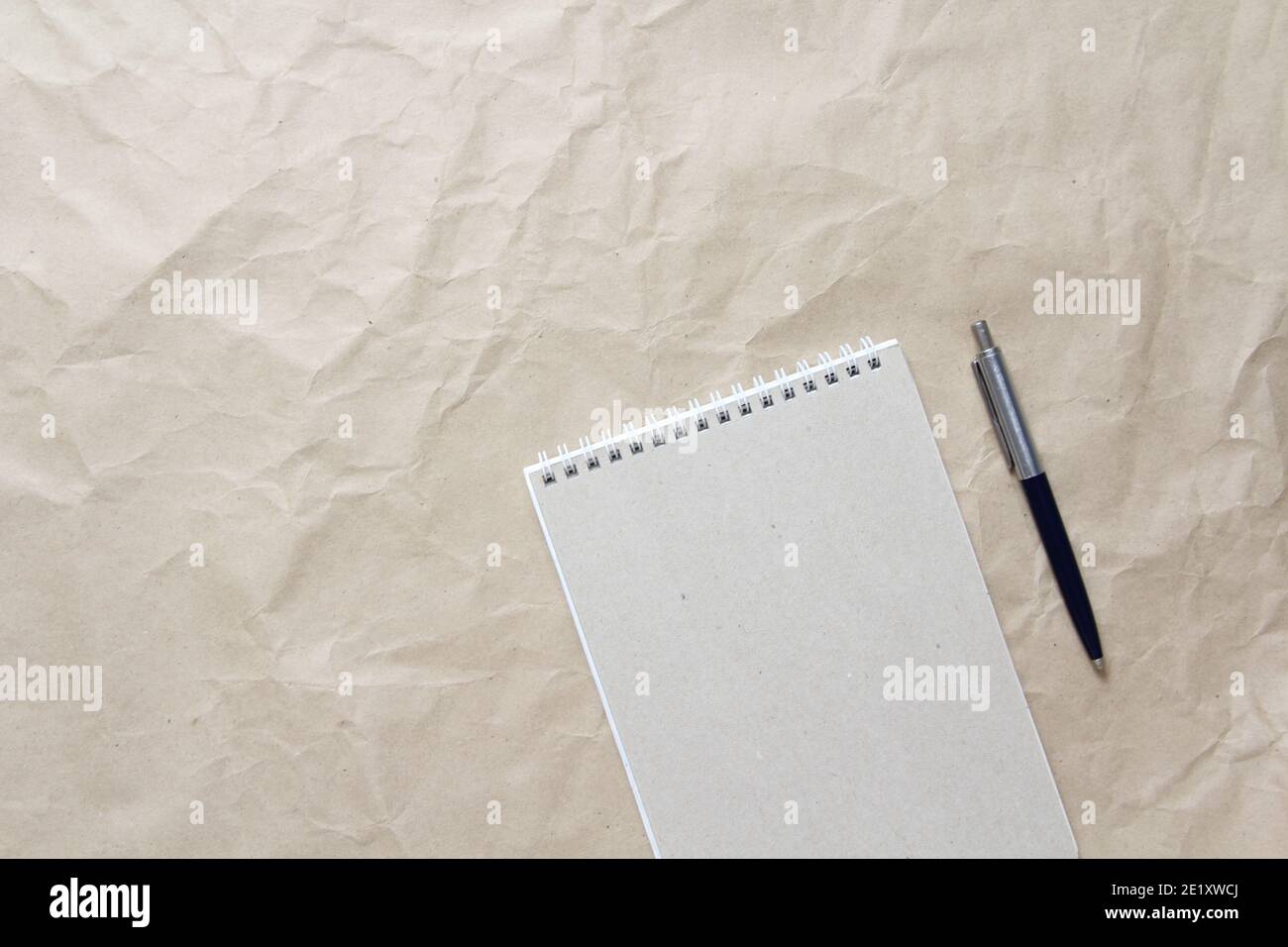 Gray notepad with white coiled spring and pen on a background of beige ...
