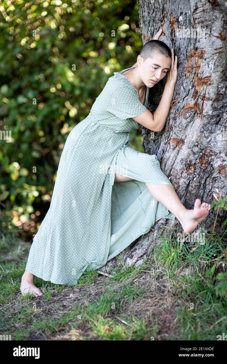 Non-binary shaved head biological female in green dress connecting with ...