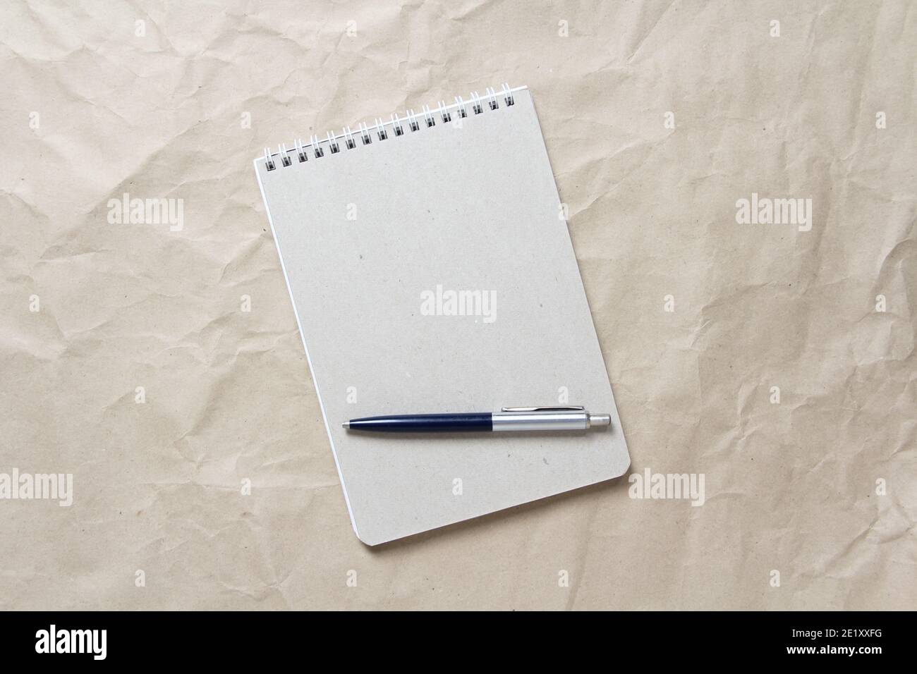 Gray notepad with white coiled spring and pen on a background of beige ...