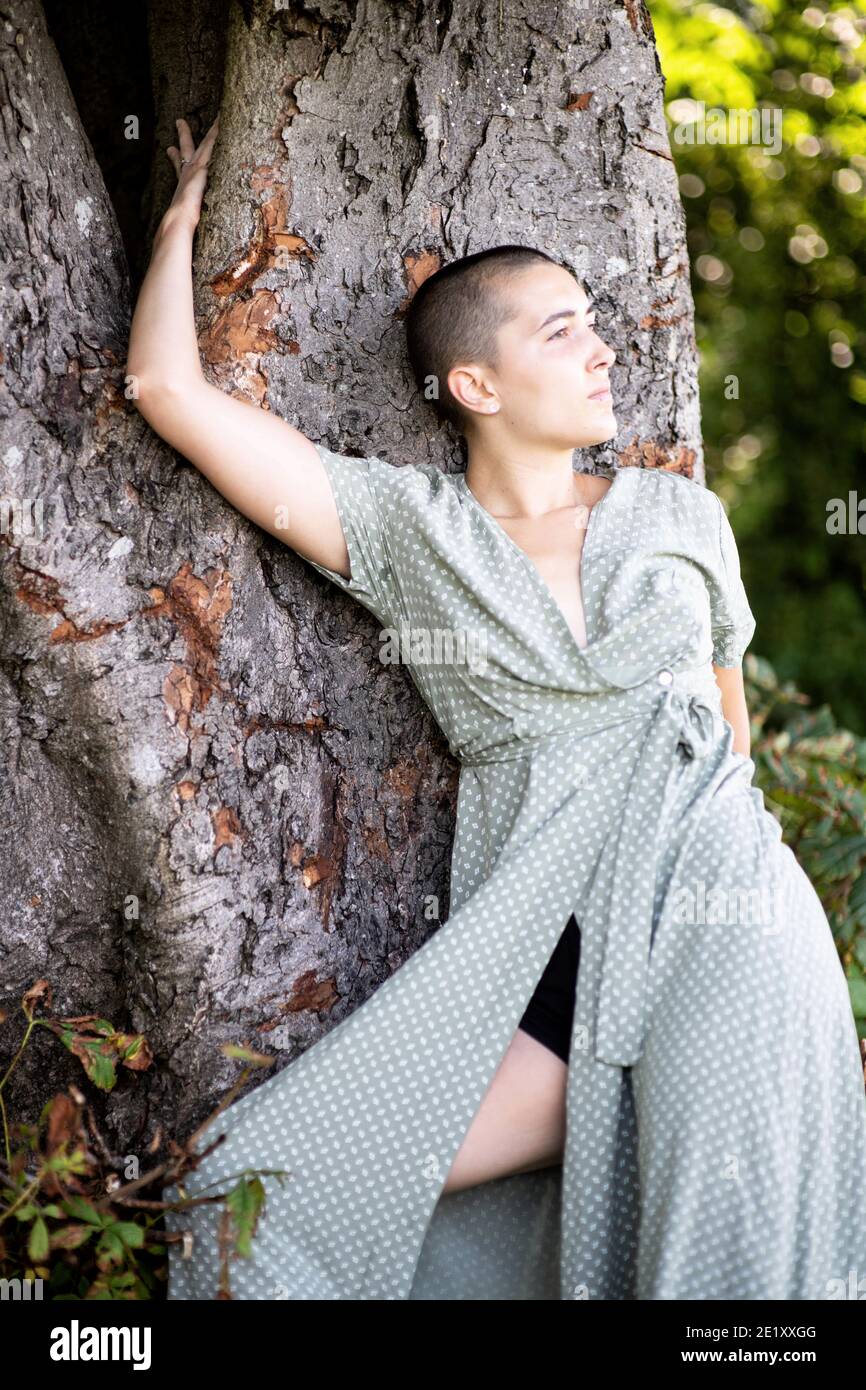 Non-binary shaved head biological female in green dress connecting with ...