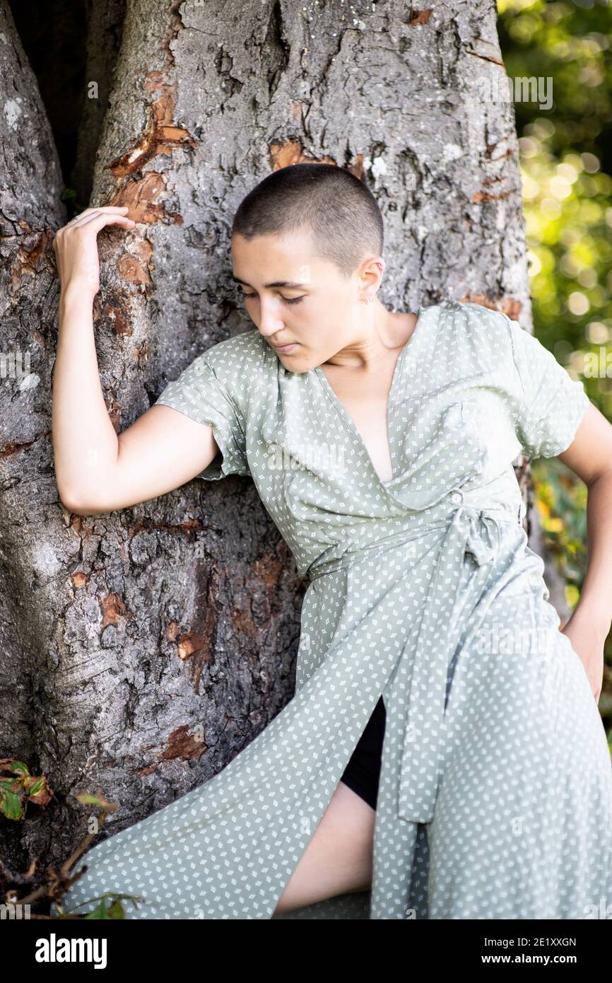 Non-binary shaved head biological female in green dress connecting with ...