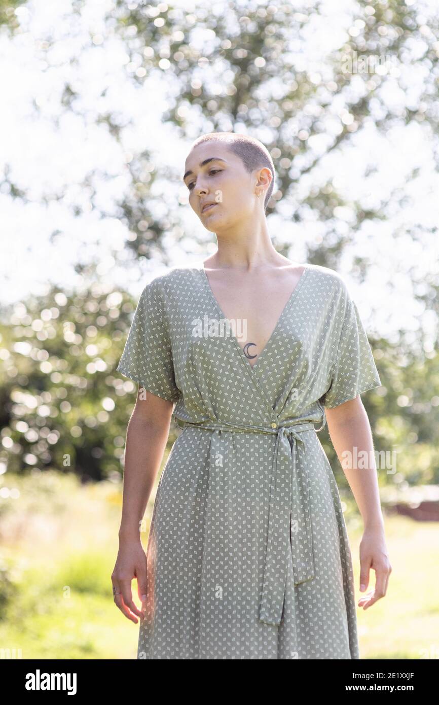 Non-binary shaved head biological female in green dress connecting with ...