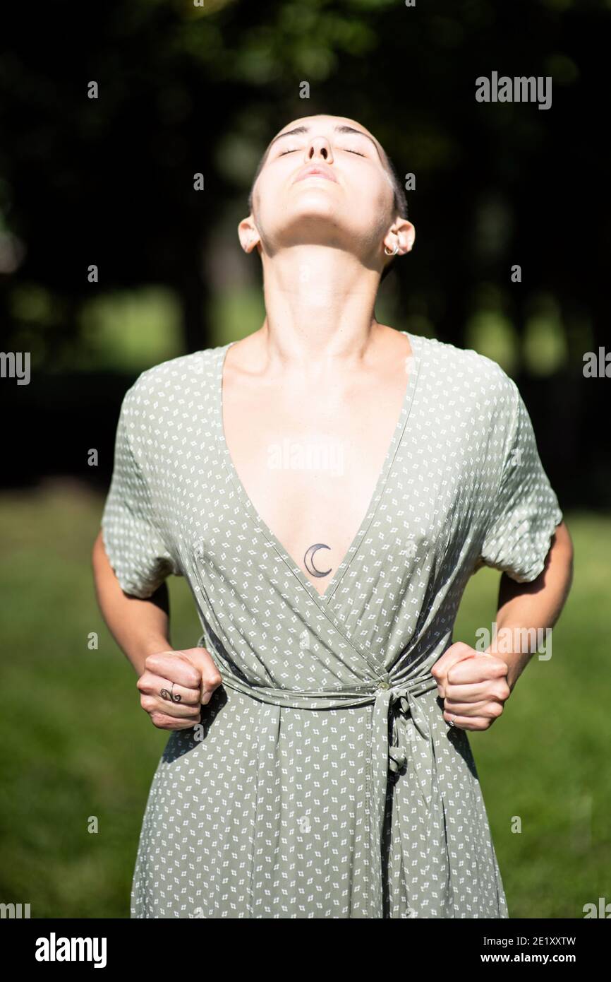 Non-binary shaved head biological female in green dress connecting with ...