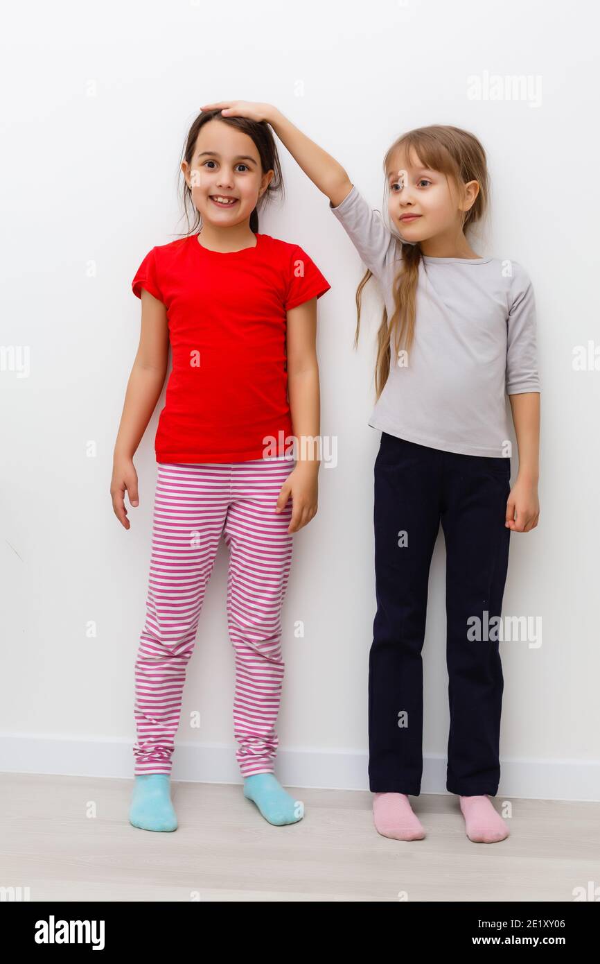 Two girls stretch up with hand on scale Stock Photo - Alamy