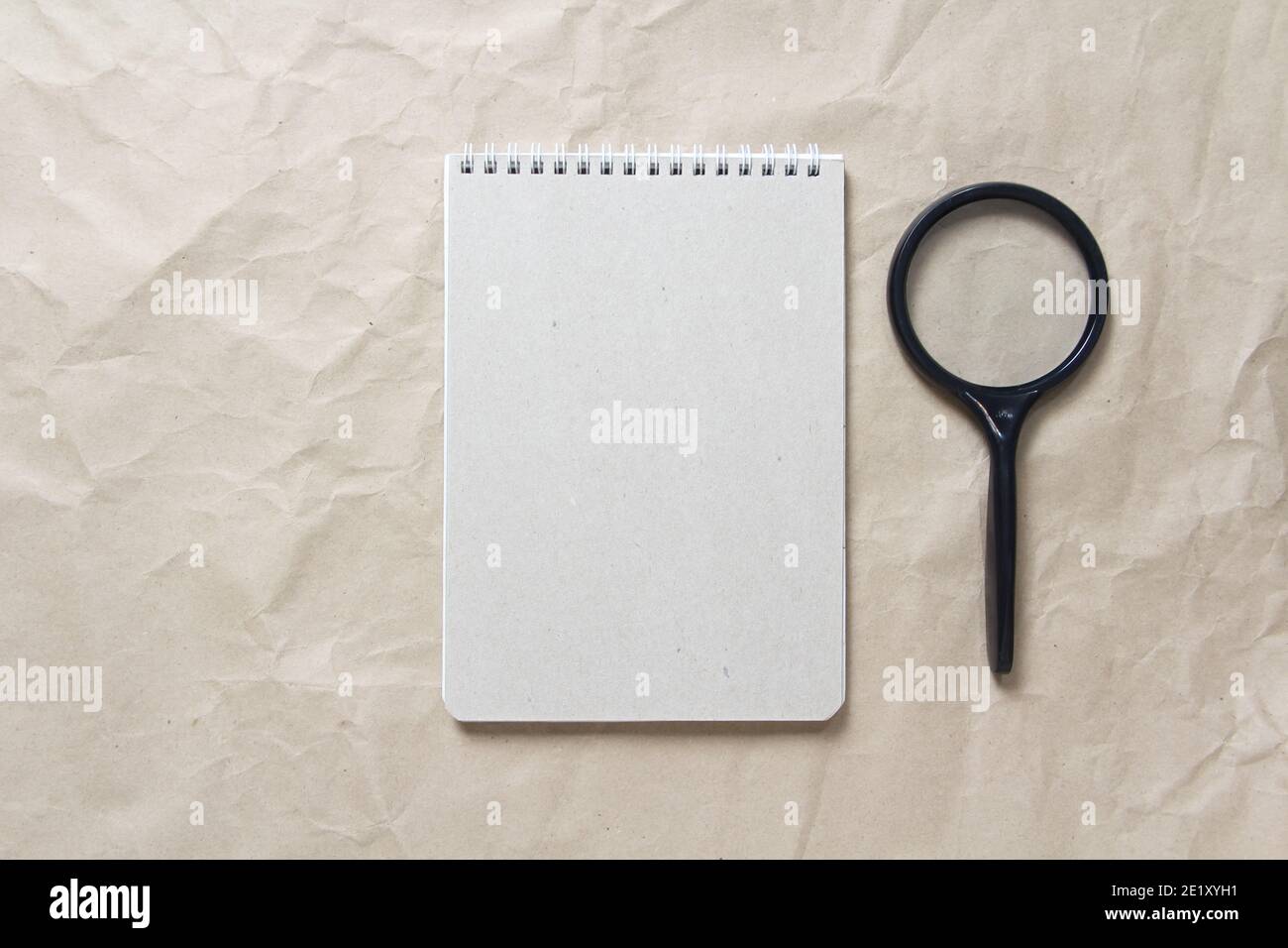 Gray notepad with white coiled spring and magnifier on a background of ...