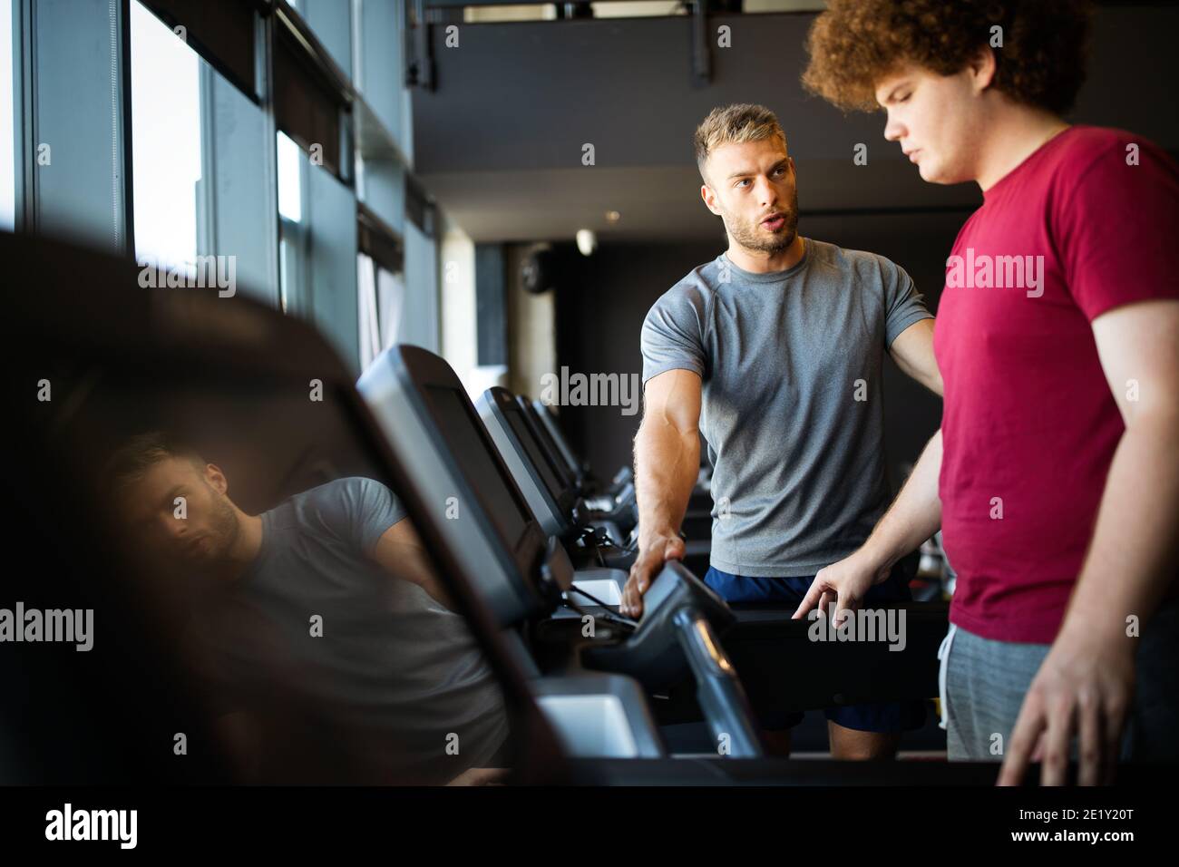 Overweight young man exercising gym with personal trainer Stock Photo ...