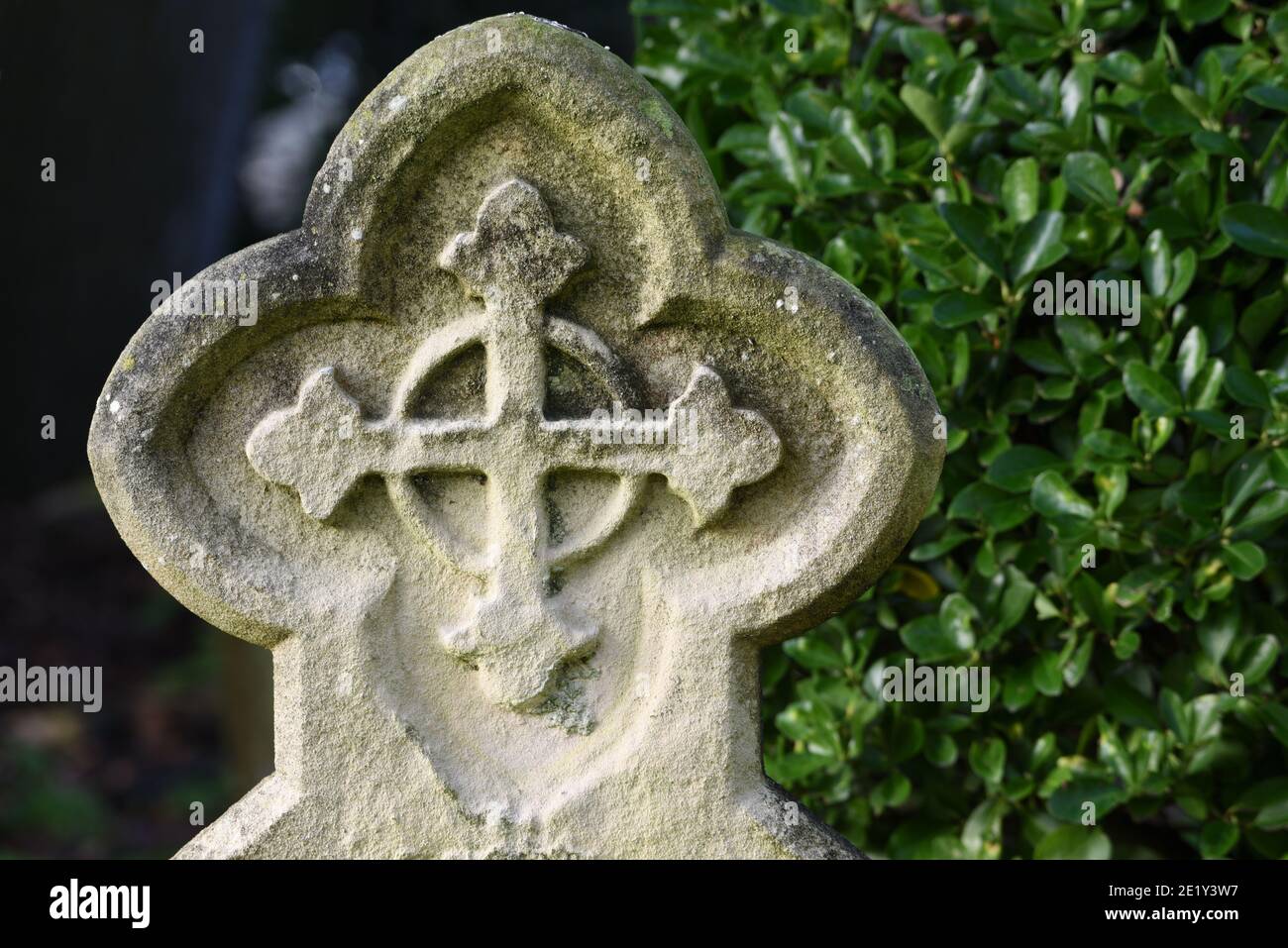 Old stone cross against green foliage in St Margaret's churchyard ...