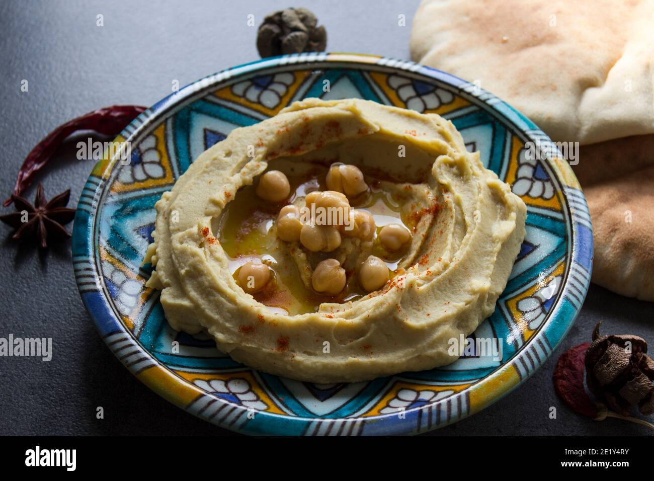 Close up photo of fresh homemade hummus on colorful ceramic plate ...