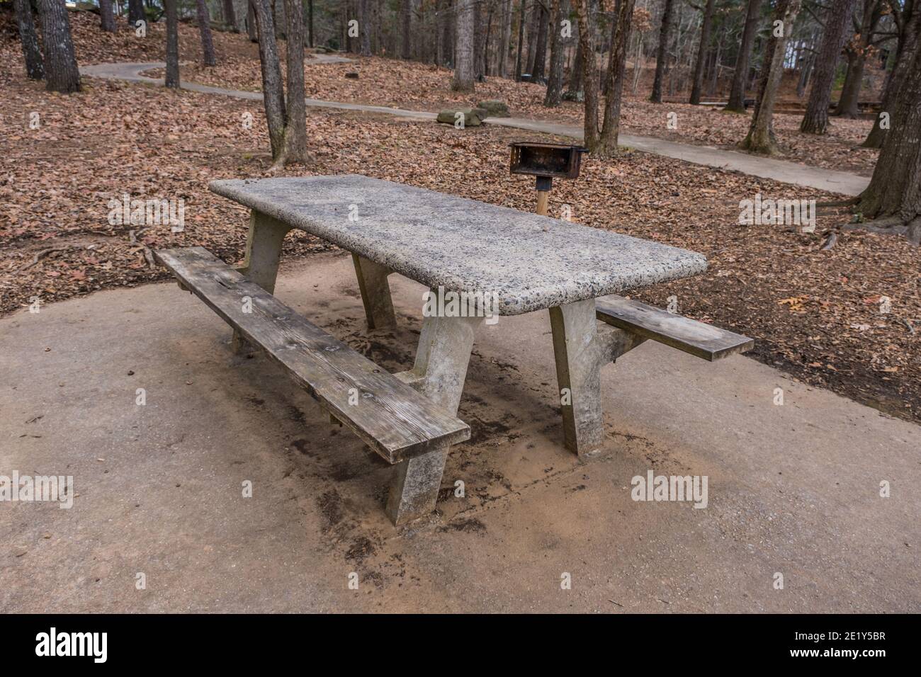 Closeup of a rustic and old picnic table sitting on a cement pad with a ...