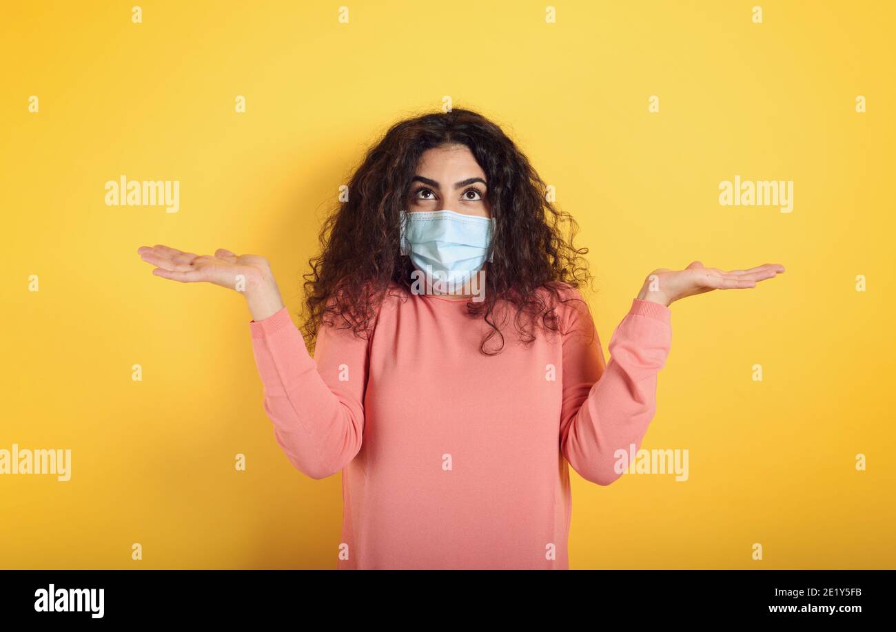 Girl with face mask is confused about covid 19. Yellow background Stock ...