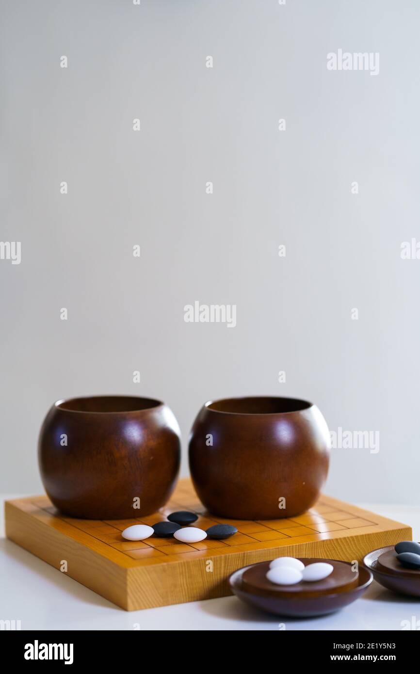 black and white stones of baduk game on wooden board showing white ...
