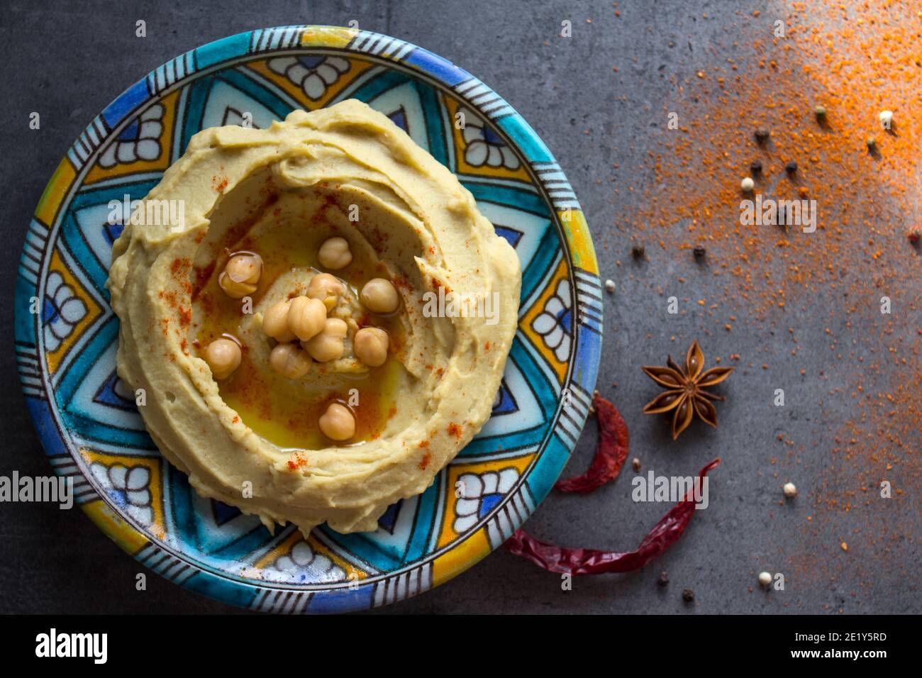 Close up photo of fresh homemade hummus on colorful ceramic plate ...