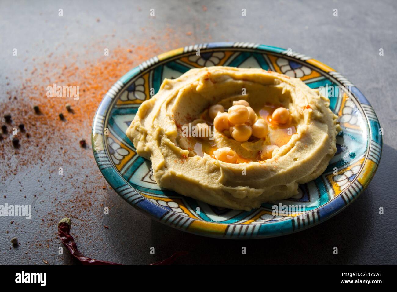 Close up photo of fresh homemade hummus on colorful ceramic plate ...
