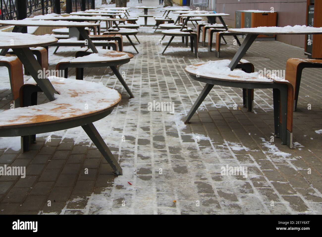 Tables and benches covered with snow stand on the city street on a ...