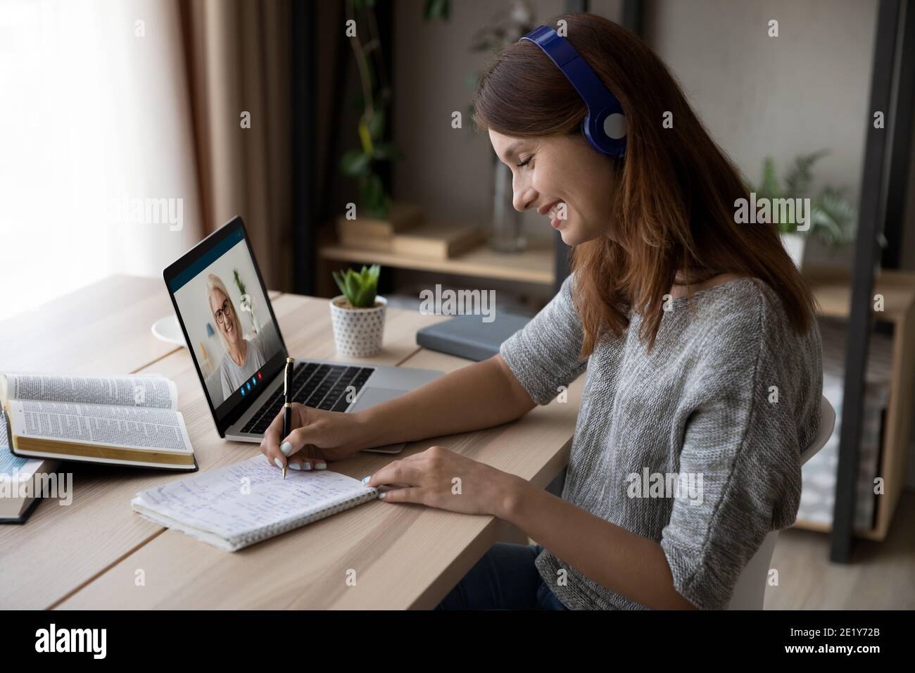 Smiling female student have online lesson with teacher Stock Photo - Alamy