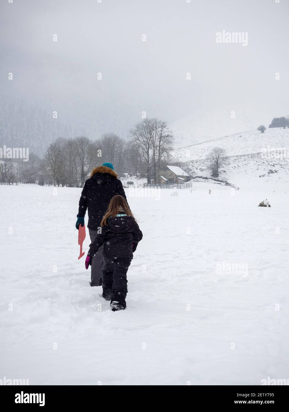 Two people walking through the snow Stock Photo - Alamy
