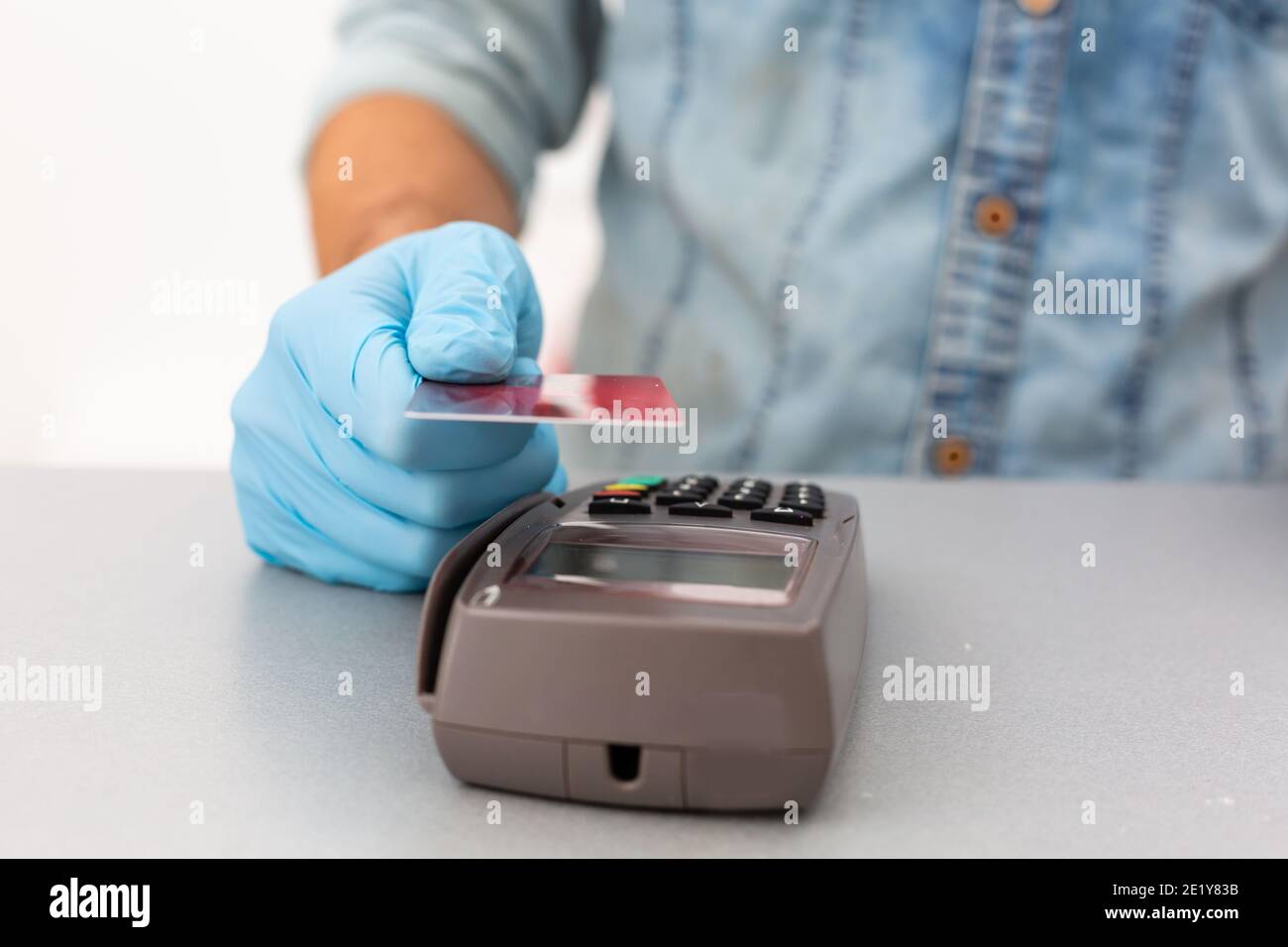 Cashier hand holding credit card reader machine and wearing disposable ...