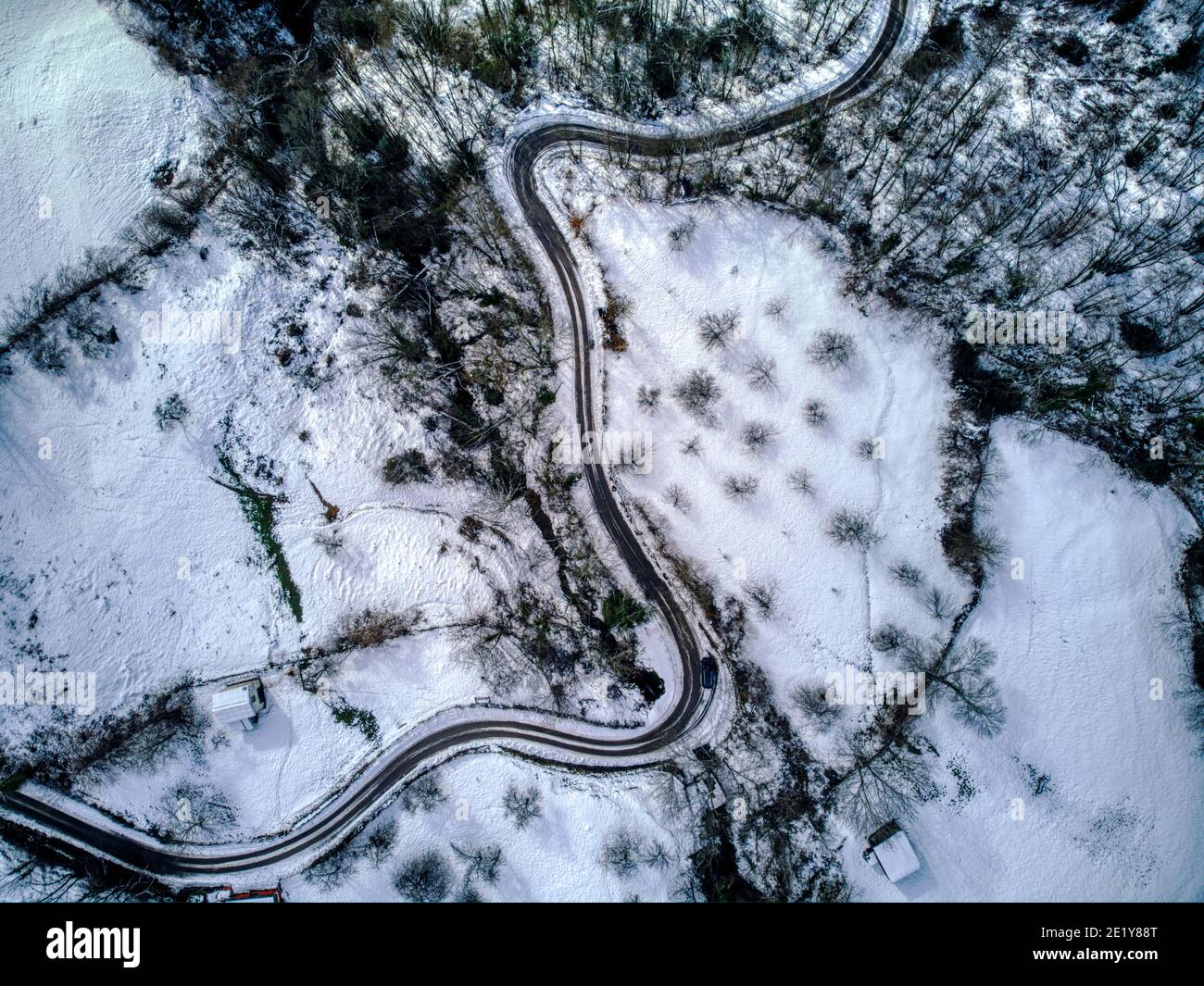 Aerial view of winding road through snowy landscape in Asturias ...