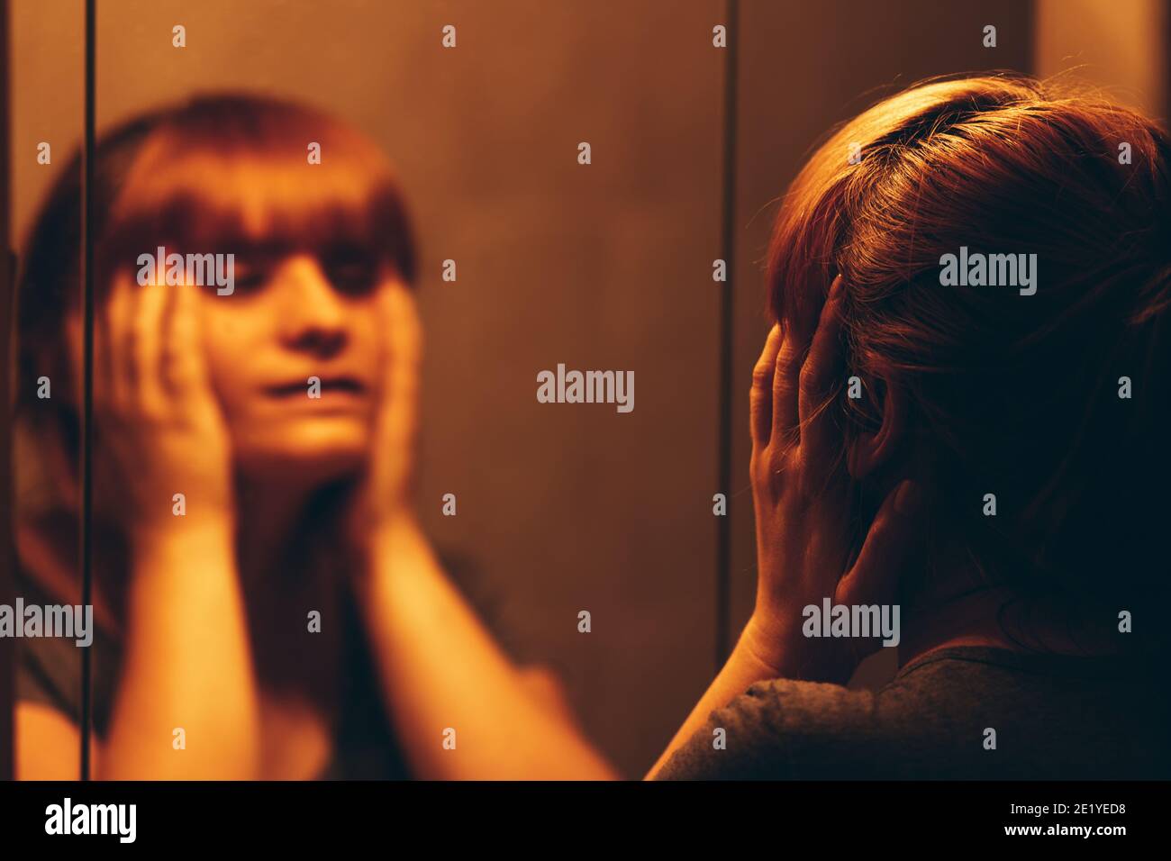 Depressed woman starring in her reflection in the mirror, alone and sad ...