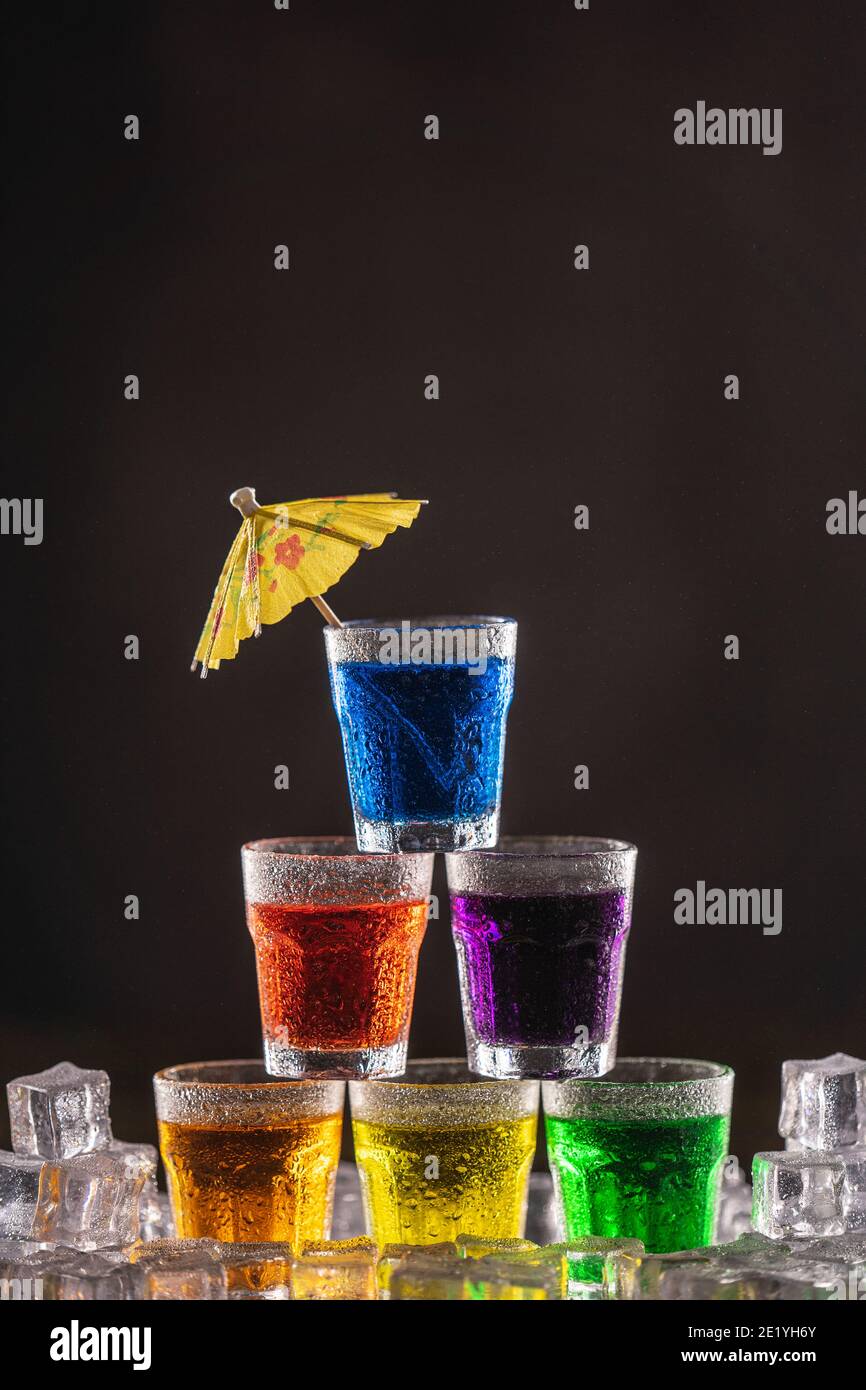 Pyramid of shots with colorful alcohol, decorated with umbrellas for ...