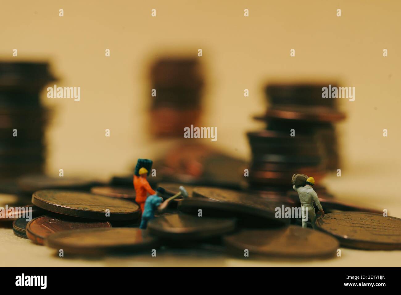 economy and work: miniature workers on coins with a yellow background ...