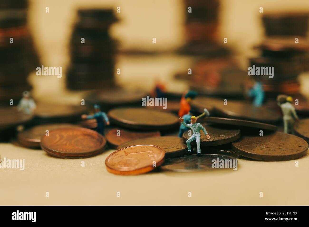 economy and work: miniature workers on coins with a yellow background ...