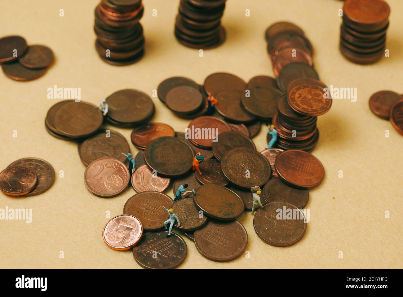 economy and work: miniature workers on coins with a yellow background ...