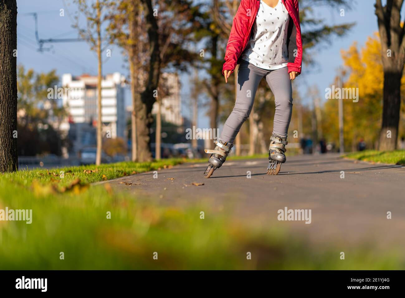 Active leisure. A sportive girl is rollerblading in an autumn park ...