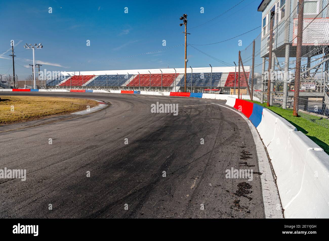 Racing track on a day off with blue sky and colored bleachers Stock ...