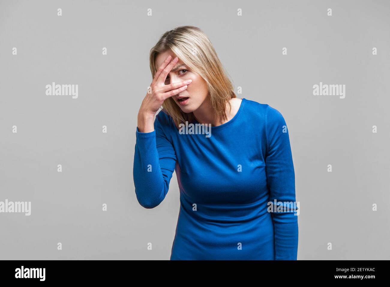 Portrait of curious young woman in elegant tight blue dress standing ...