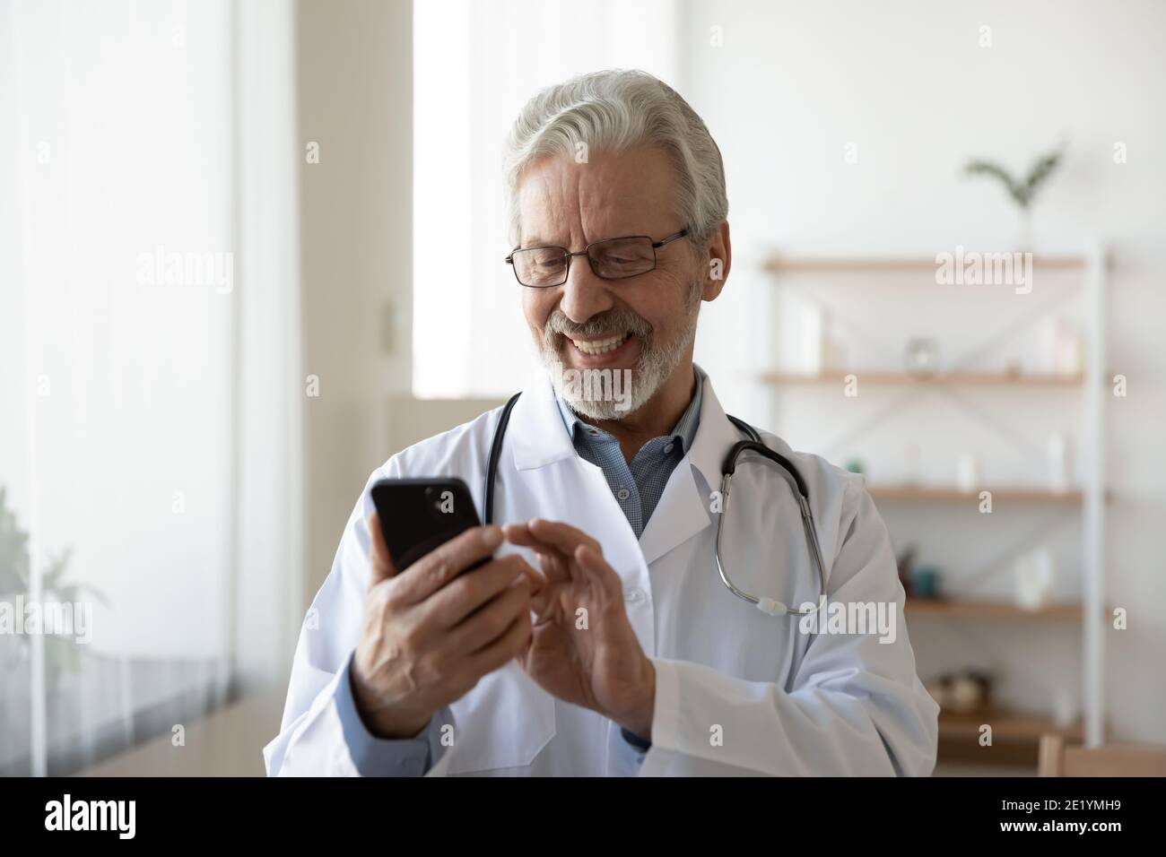 Elderly doctor using phone in hi-res stock photography and images - Alamy