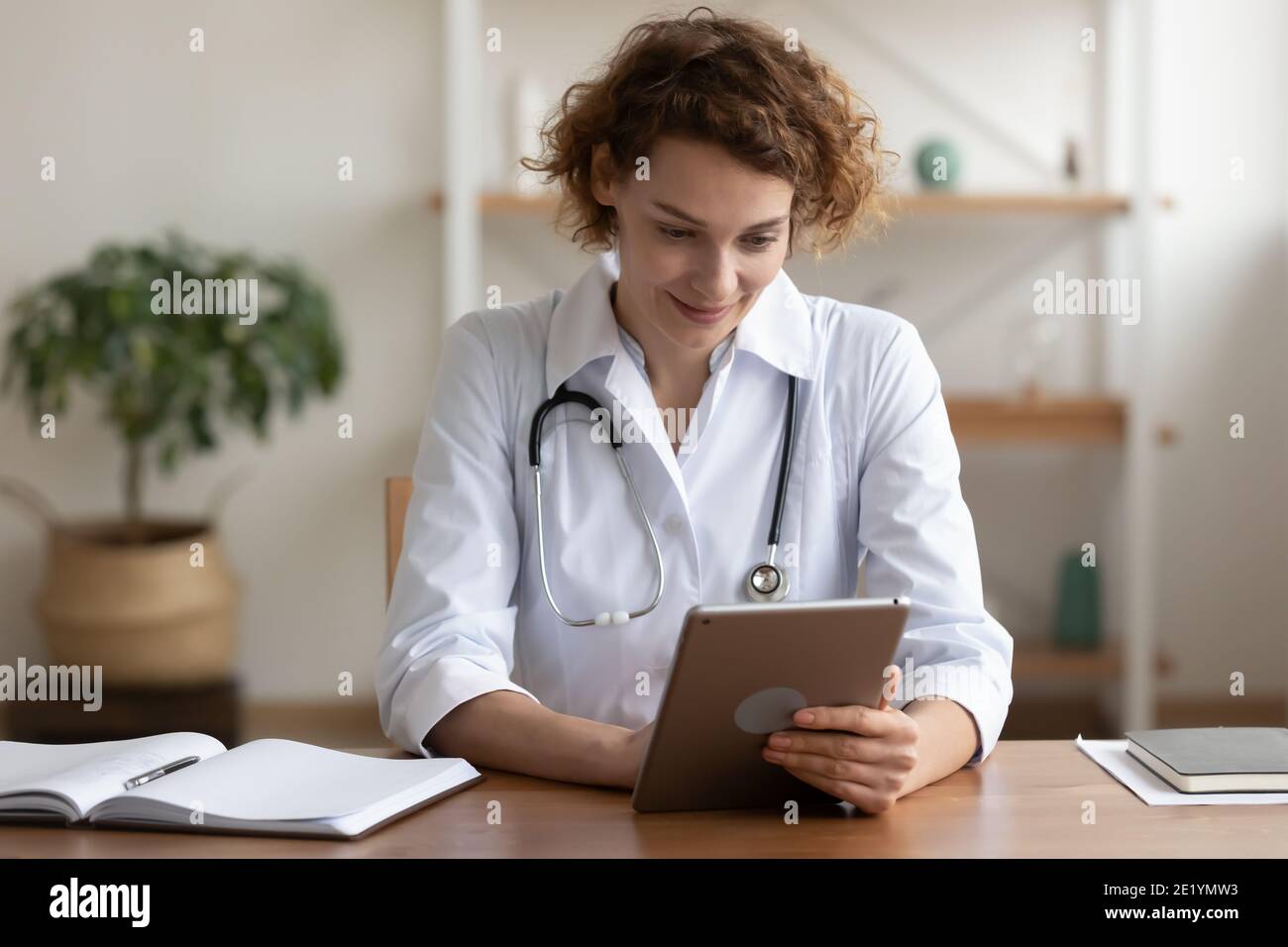 Happy young female general practitioner using digital computer tablet ...