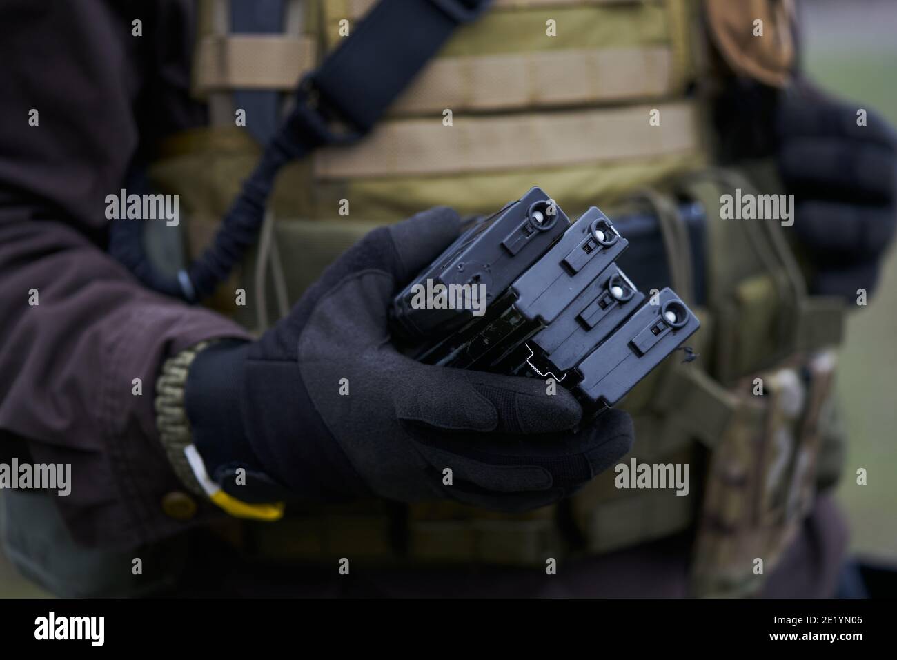 Airsoft player in protective gloves holds magazines for a machine gun ...