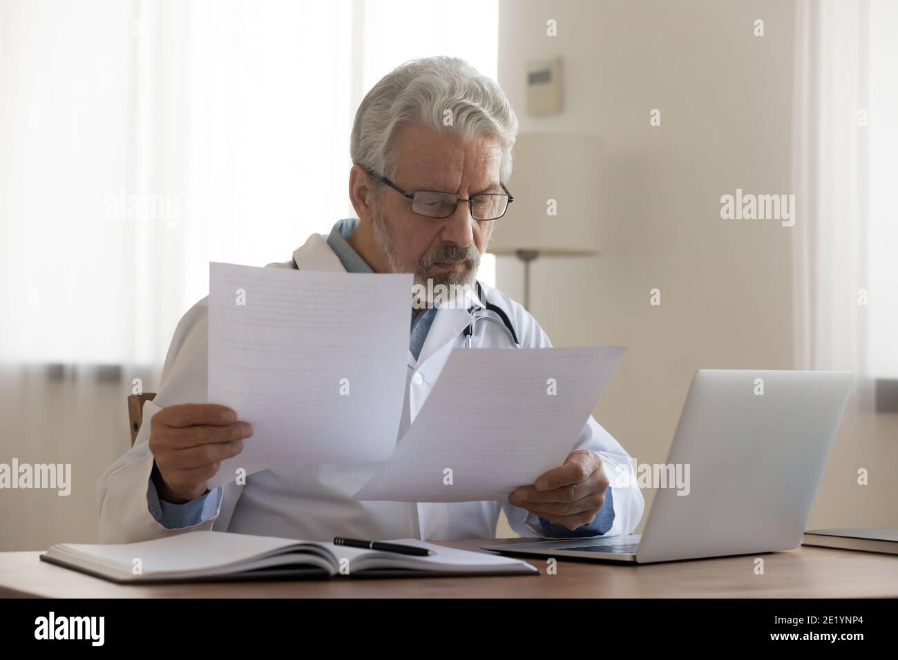 Focused middle aged senior male general practitioner doing medical ...
