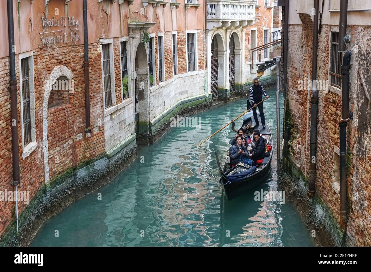 Traditional Venetian gondola with tourists on rio di Santa Maria ...