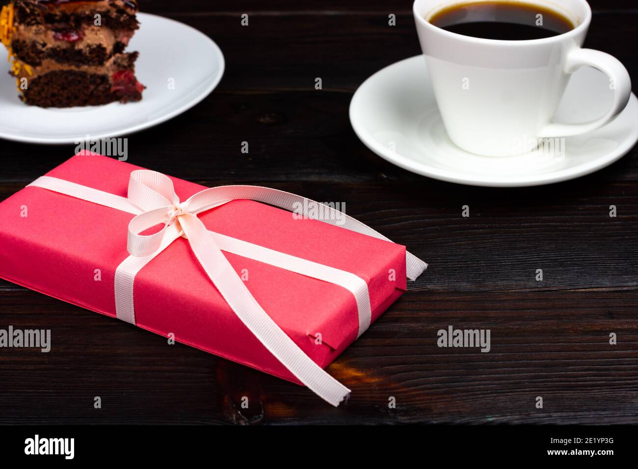 Romantic pink gift with a white ribbon and a cup of coffee on a dark ...