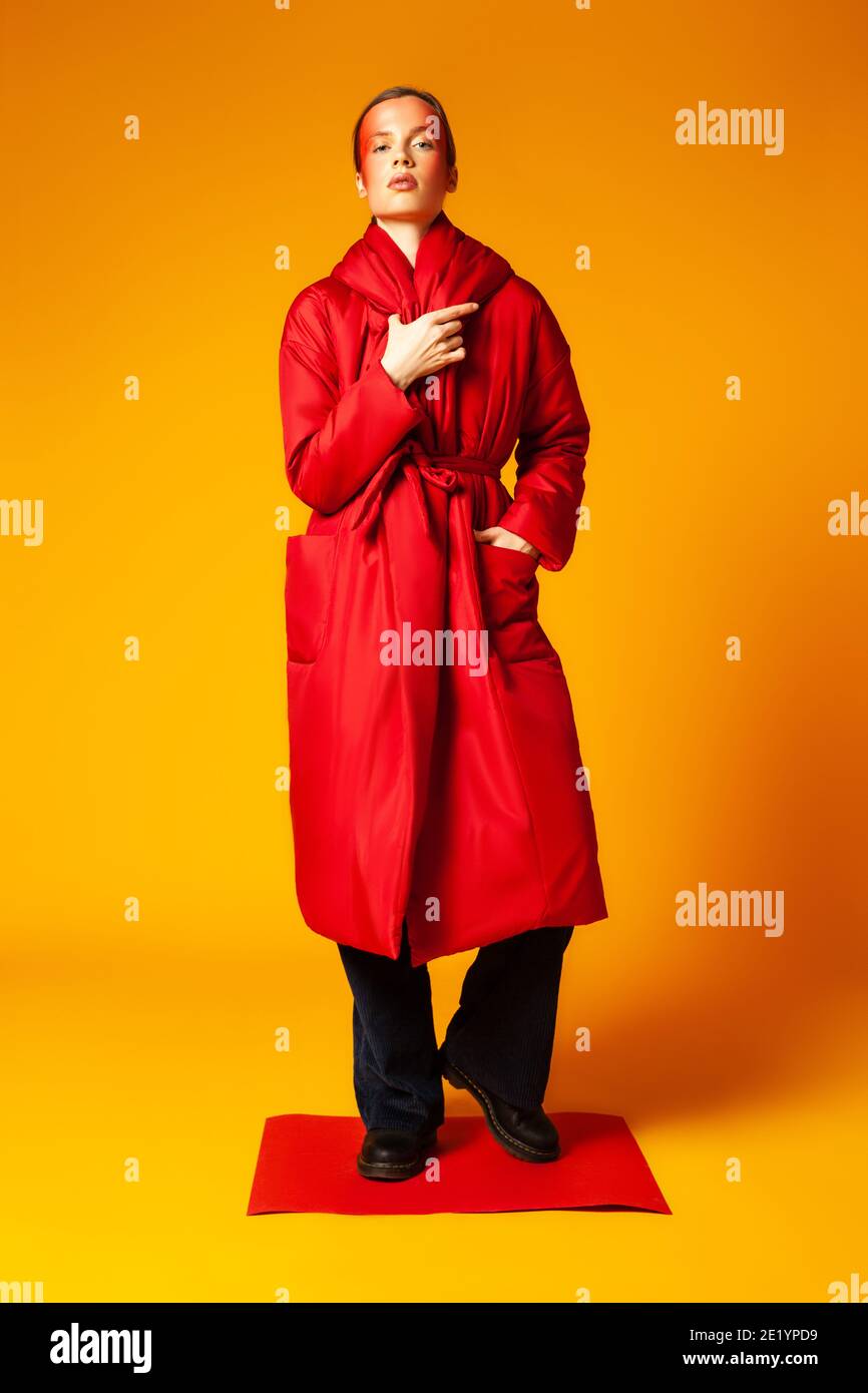 Female model in trendy red coat against yellow background Stock Photo ...