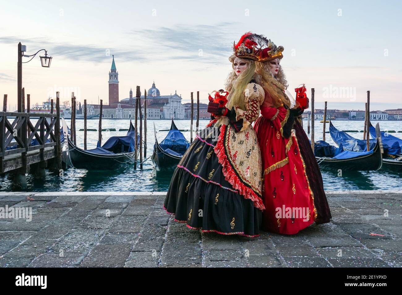Two women dressed in traditional decorated costumes and painted masks ...